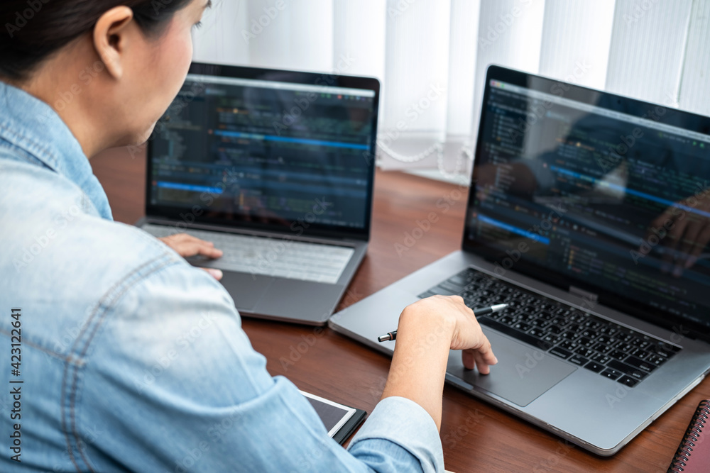 Asian programmer woman looking on multiple laptop screen and holding ...