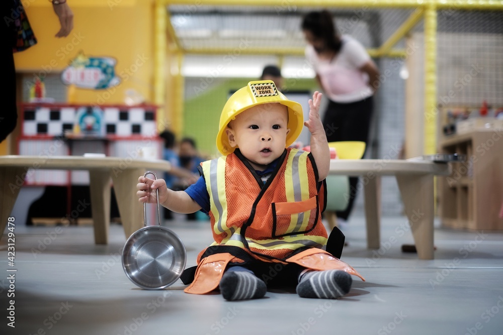 An Asian boy dressed in an engineer suit playing in a children's theme ...