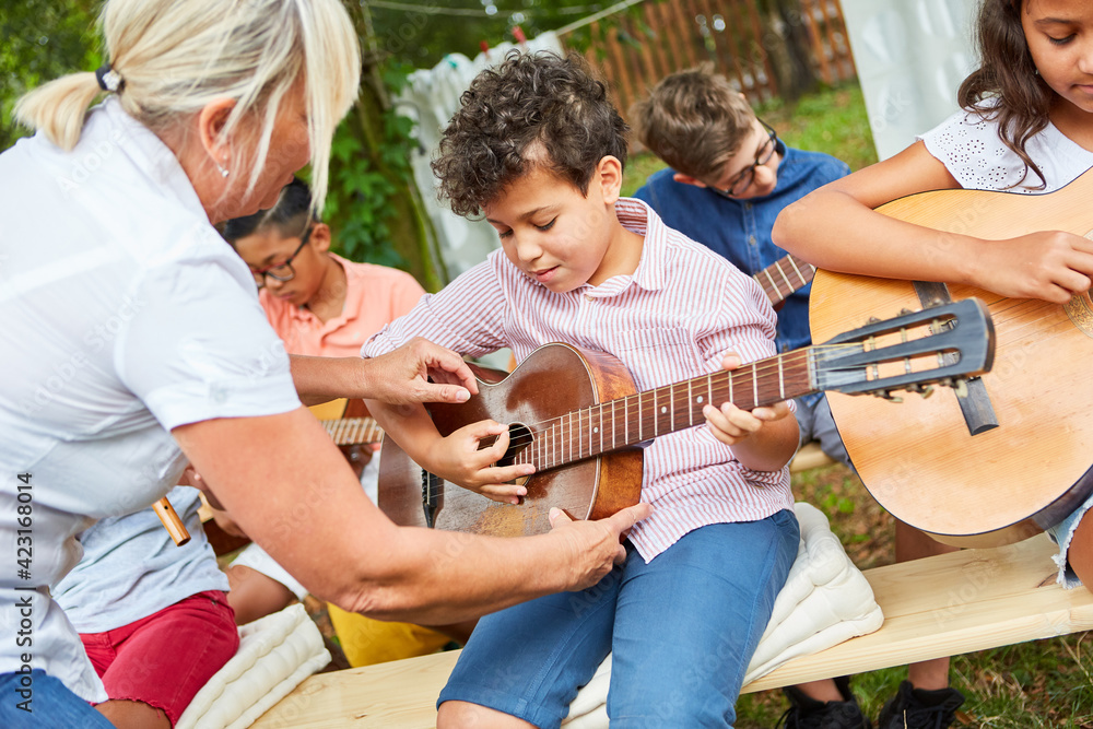 Teacher helps child learn to play the guitar Stock Photo | Adobe Stock