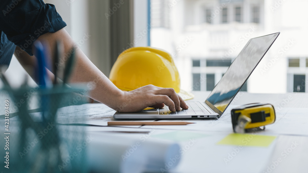 Young man with a laptop plotting a system of building structures in ...