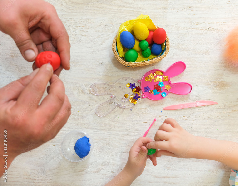Child with father making funny Easter eggs from colorful plasticine ...