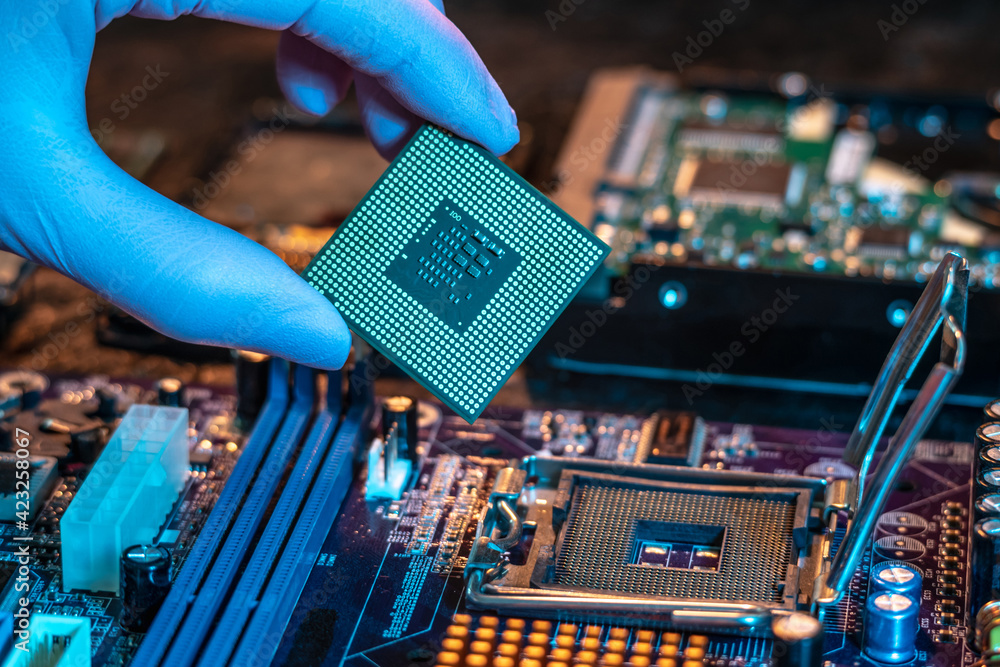 Engineer's gloved hand is holding the CPU chip on the background of the ...