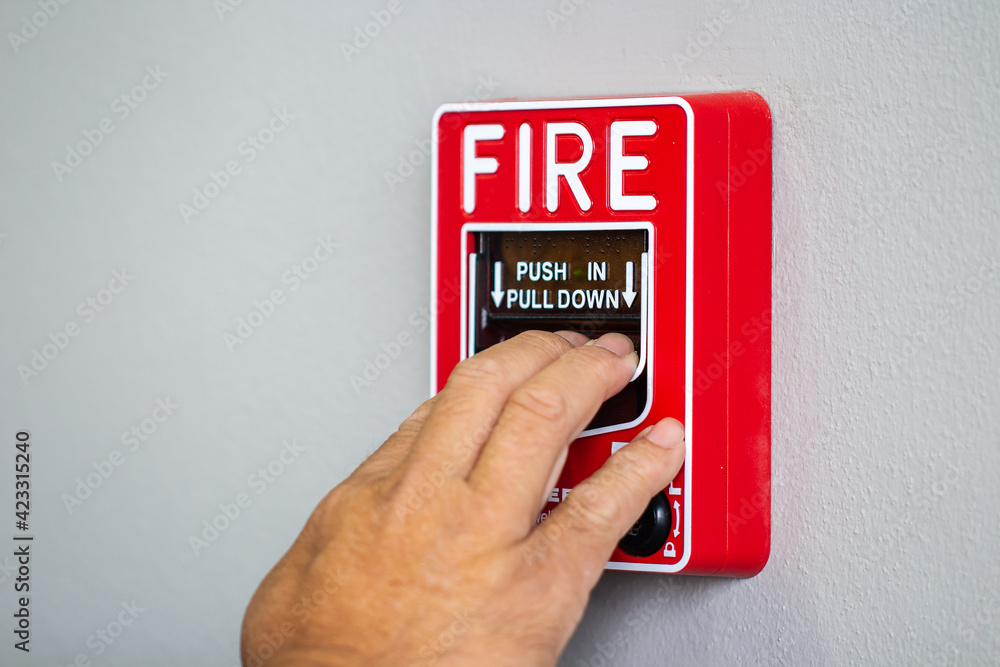 Fire alarm switch, The hand of man is pulling fire alarm on the wall ...