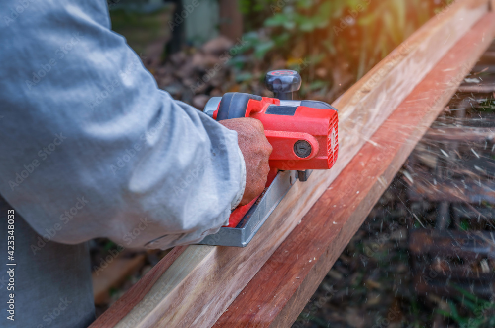 Hand of carpenter using electric planer with wooden plank in carpentry ...
