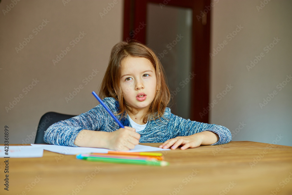 Foto de School girl drawing and writing a picture with crayons, using ...