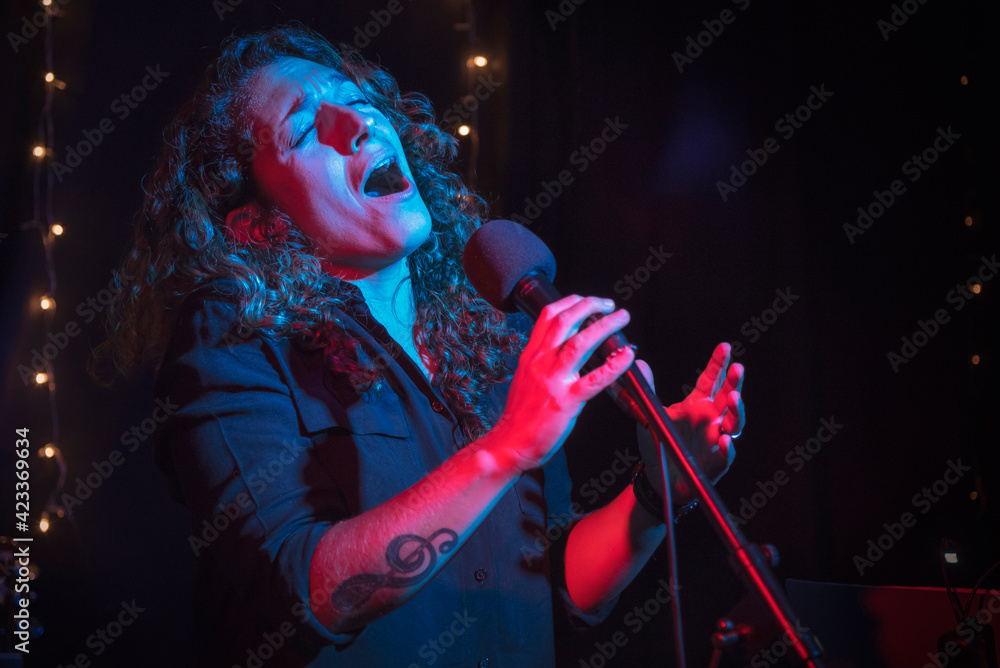Curly hair woman performing music show with microphone. Rock pop female ...