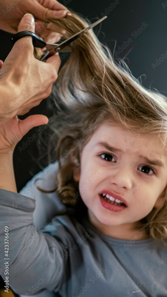 Little boy, toddler is afraid and doesn't want to cut his hair. A baby ...