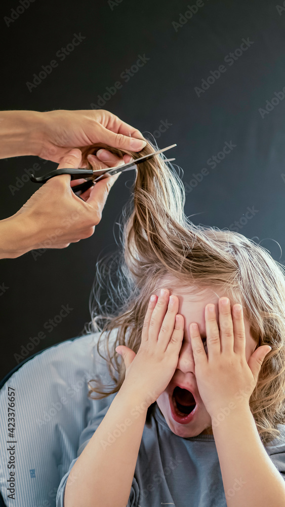 Little boy, toddler is afraid and doesn't want to cut his hair. A baby ...