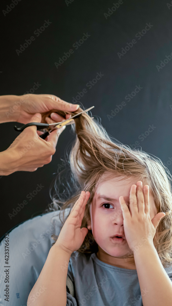 Little boy, toddler is afraid and doesn't want to cut his hair. A baby ...