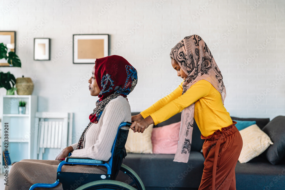 Caring muslim child helping parent in wheelchair with disability to ...