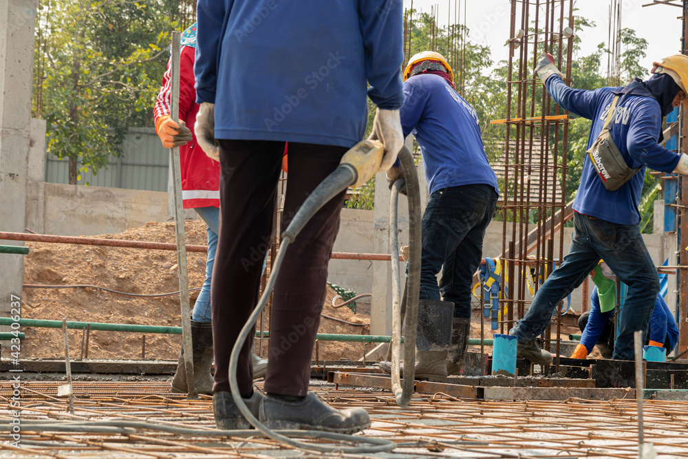 Workers put jeans on their feet holding concrete vibrators in their ...