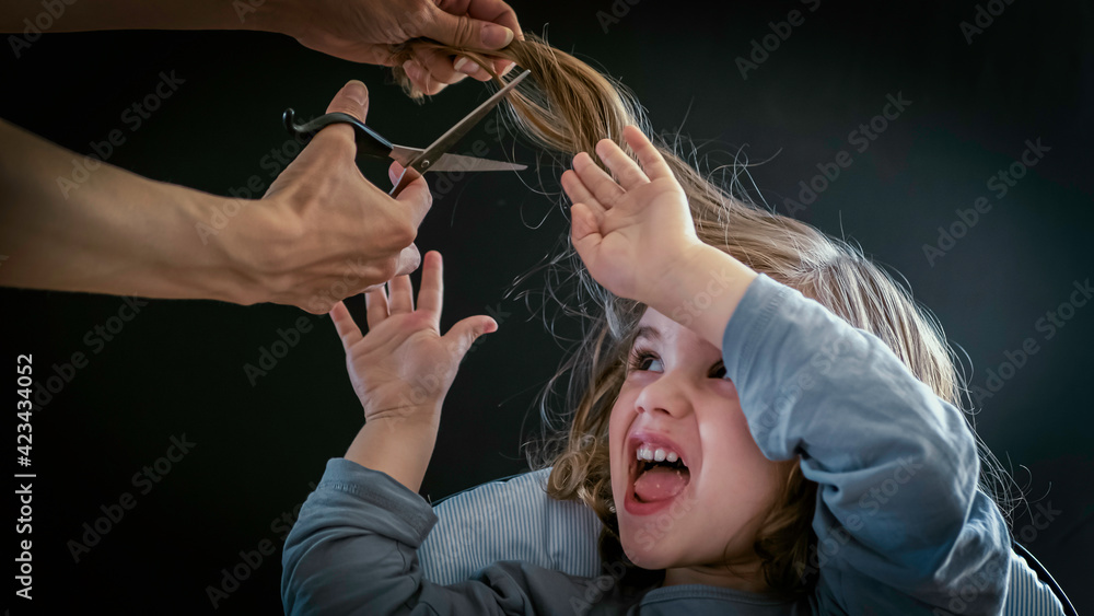 Little boy, toddler is afraid and doesn't want to cut his hair. A baby ...