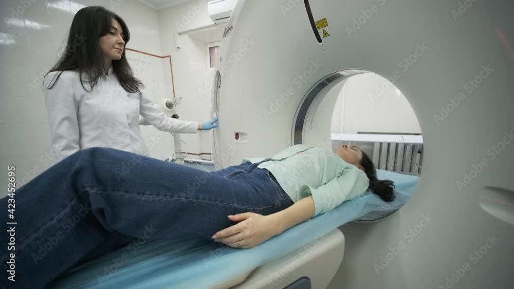Female patient is undergoing CT or MRI scan under supervision of a ...