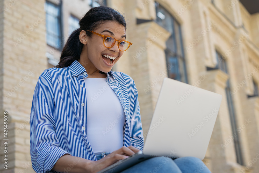 Excited African American woman using laptop computer shopping online ...