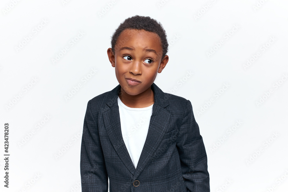 Picture of confused cute little dark skinned schoolboy in jacket ...