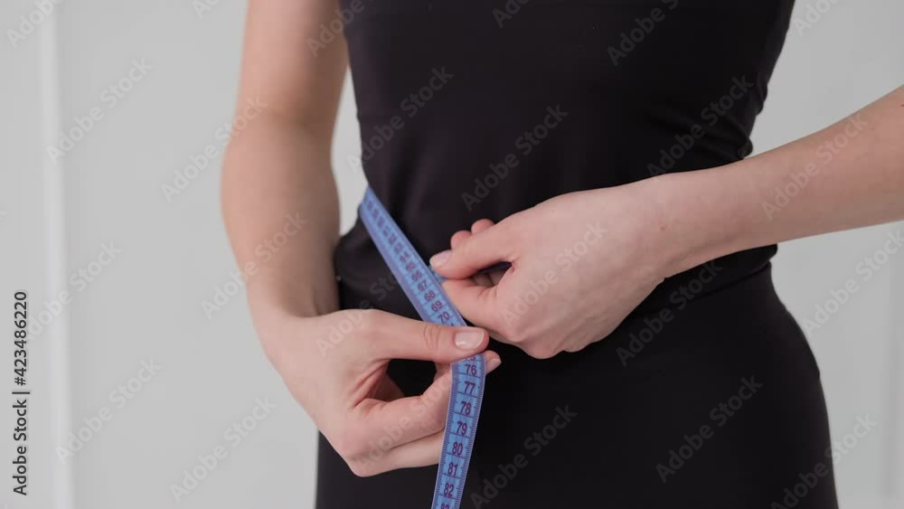 Young woman measuring her waist. Close-up of fit female measuring waist ...
