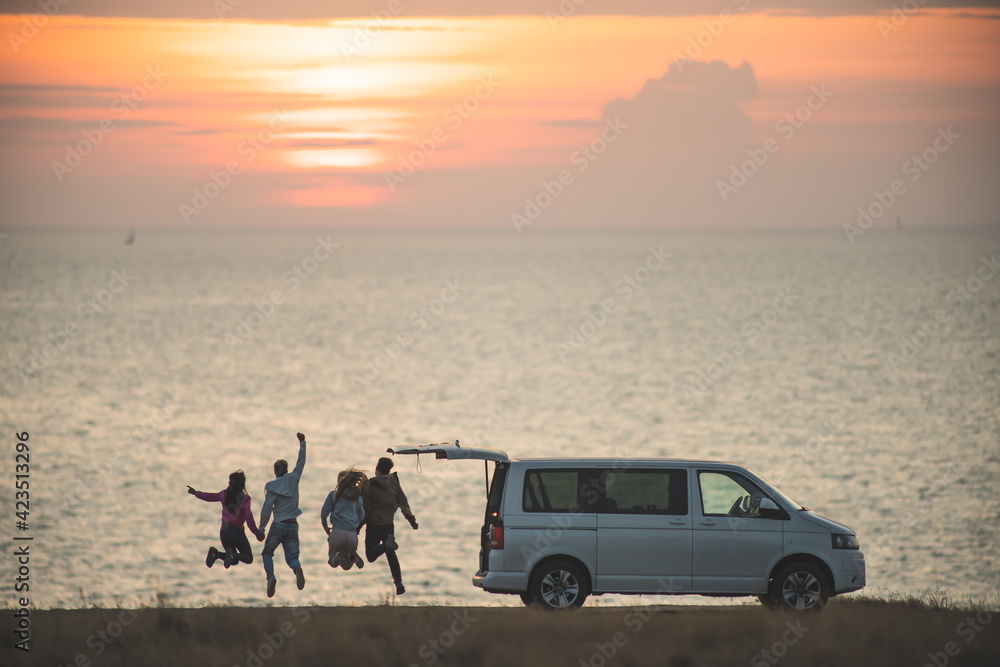 The four friends have fun near the minivan against the sunset sky Stock ...