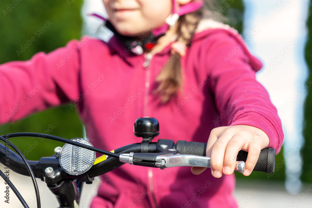 Little child, young school age cyclist riding a bike pressing the brake ...