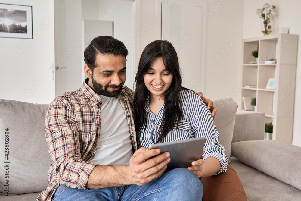 Happy indian family couple using digital tablet computer at home ...