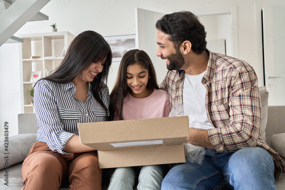 Happy indian family with child daughter unpacking parcel at home ...