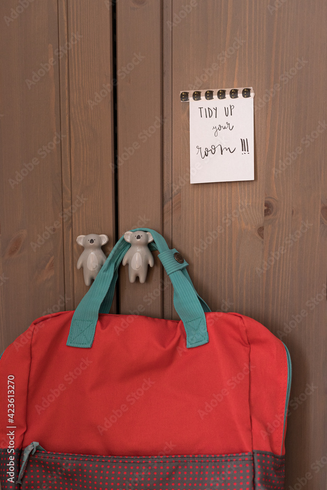 School bag hanging from a ceramic koala handle wardrobe in a child room ...