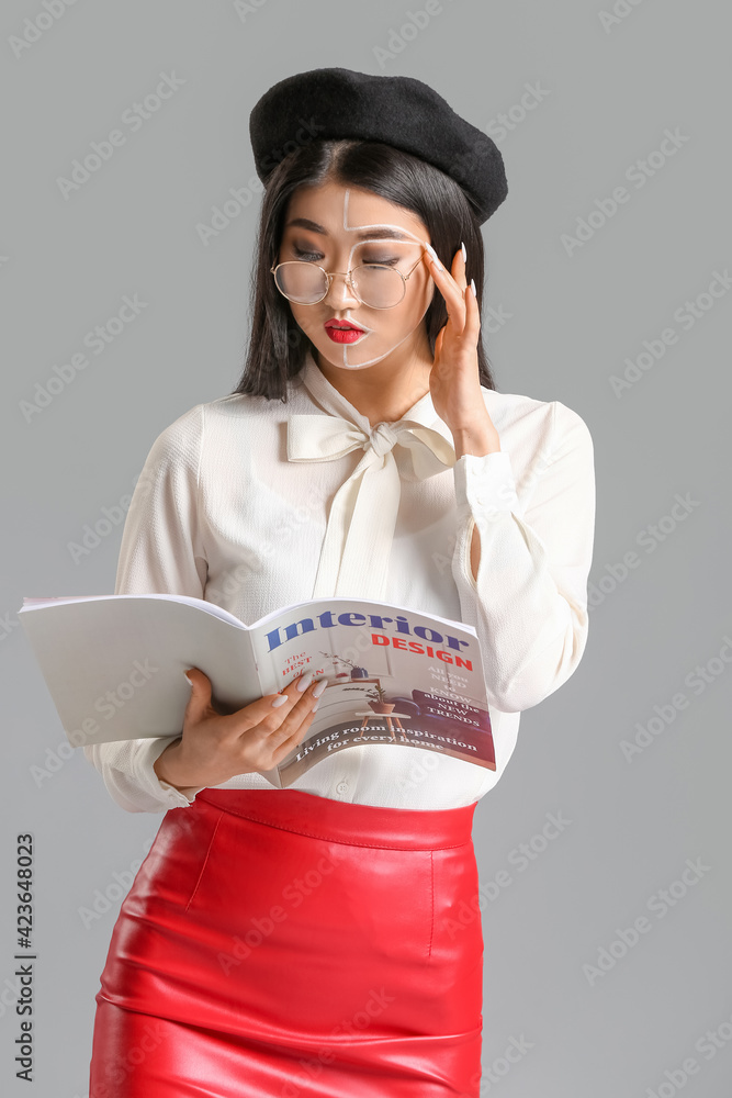 Portrait of stylish Asian woman with magazine on grey background Stock ...