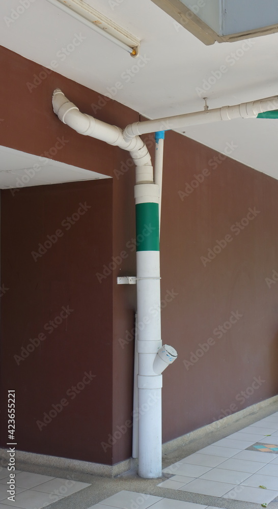 Closeup downspout connected to rain gutter at rooftop, runs through ...