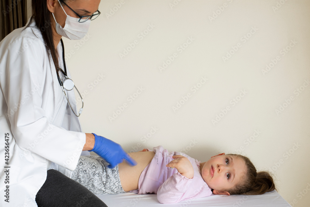 chubby little girl in pediatric examination by her doctor. Doctor examining the abdominal ...