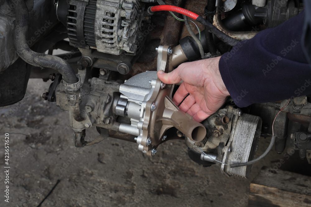 Car mechanic replacing water pump at modern common rail diesel engine ...
