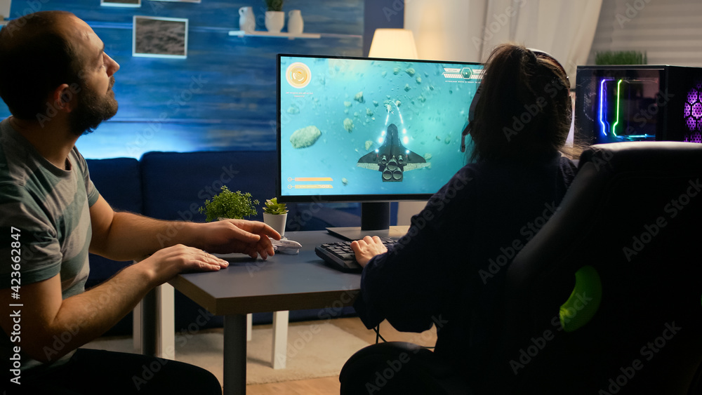 Pro gamer couple playing space shooter games sitting on gaming chiar ...