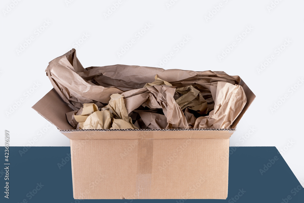 Open cardboard box on a bue gray table, with paper filling. For safe ...