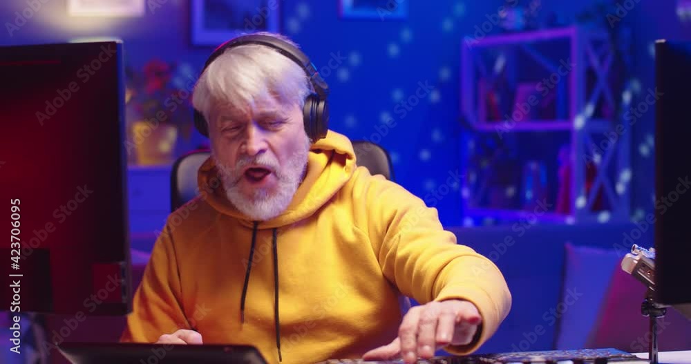 Close up of Caucasian joyful grey-haired man DJ in headphones using ...