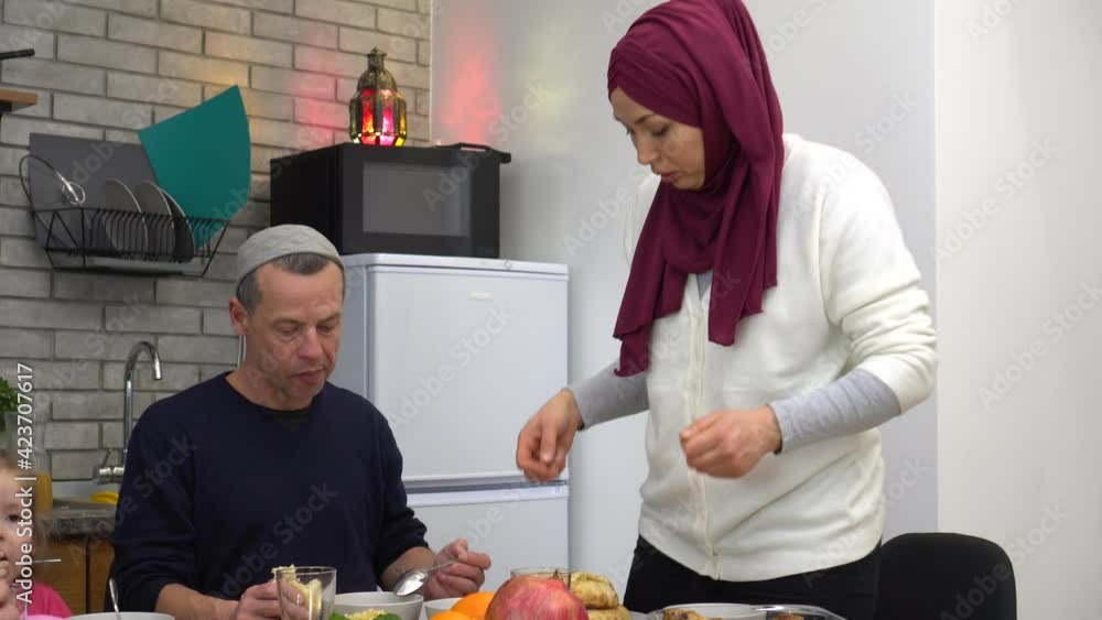 Fasting Muslim family sits together at the table during Ramadan at home ...
