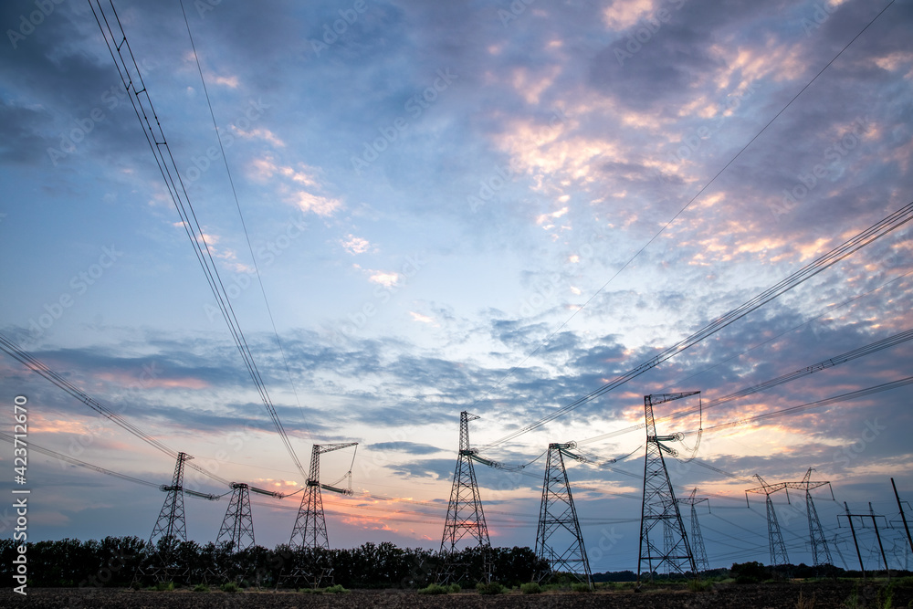 Electrical pylons and high voltage power lines at sunset background ...