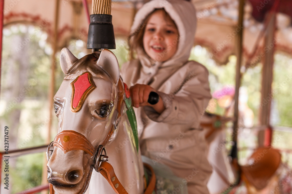 Little girl rides a carousel in an amusement park. Happy child Stock ...