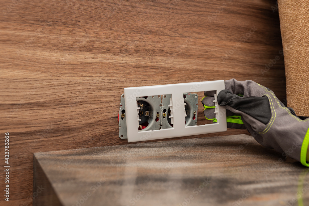 Installing electrical outlets. The electrician installs a decorative ...