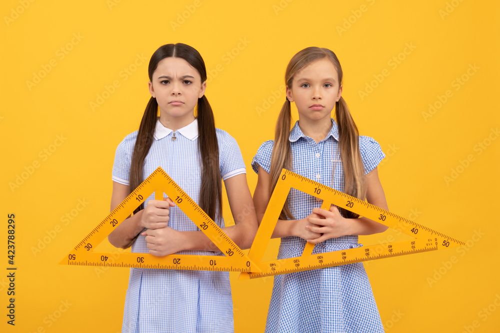 Unhappy school age children hold triangular rulers for geometry lesson ...