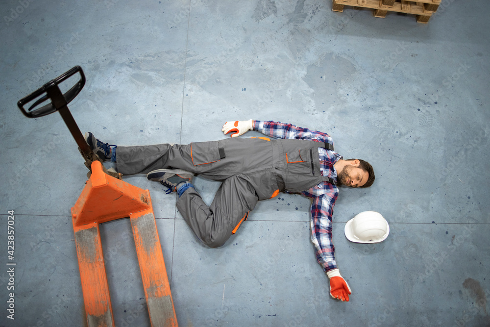 Injury at work. Warehouse worker lying unconscious on the concrete ...