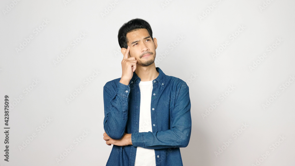 Young asian man serious thinking while standing over isolated grey ...