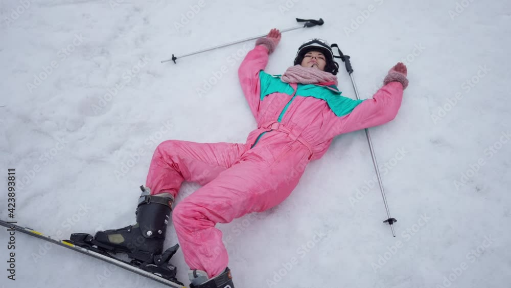 Wide shot top view of relaxed Caucasian young woman in ski suit lying ...
