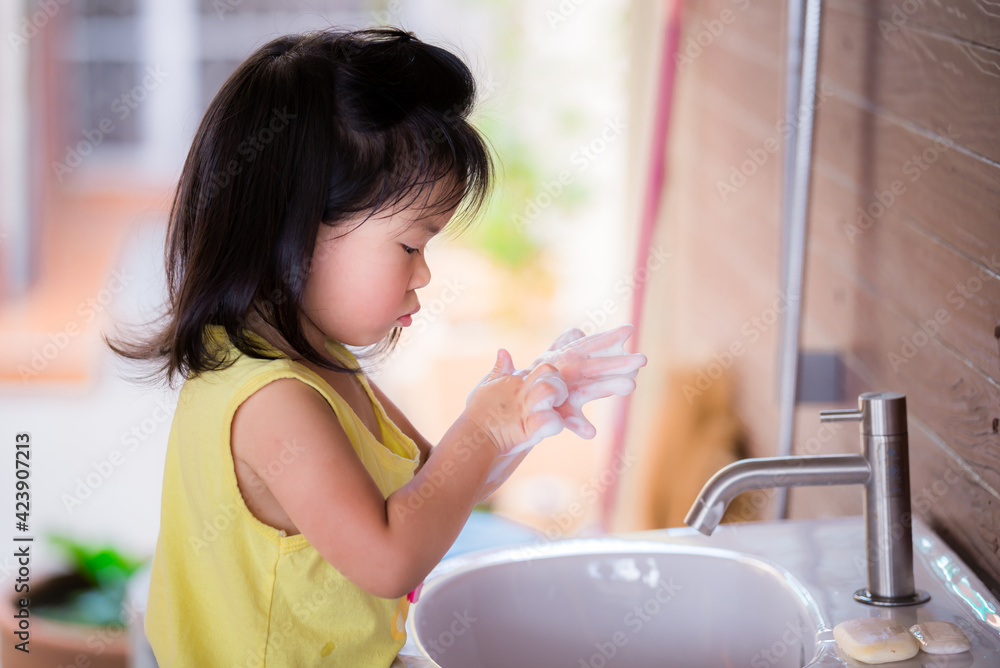 Cute Asian girl washed her hands with soap in the white sink. Children ...