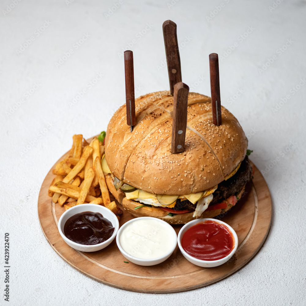 Huge size hamburger cut into four quarters with knives stuck in. Fast ...
