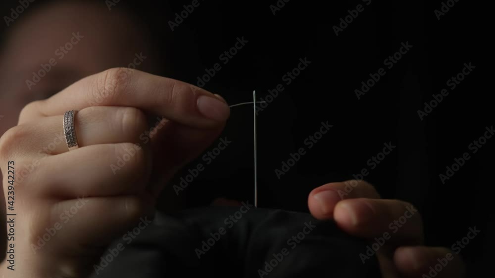 slow motion shot of thread passing through sewing needle. woman sewing ...