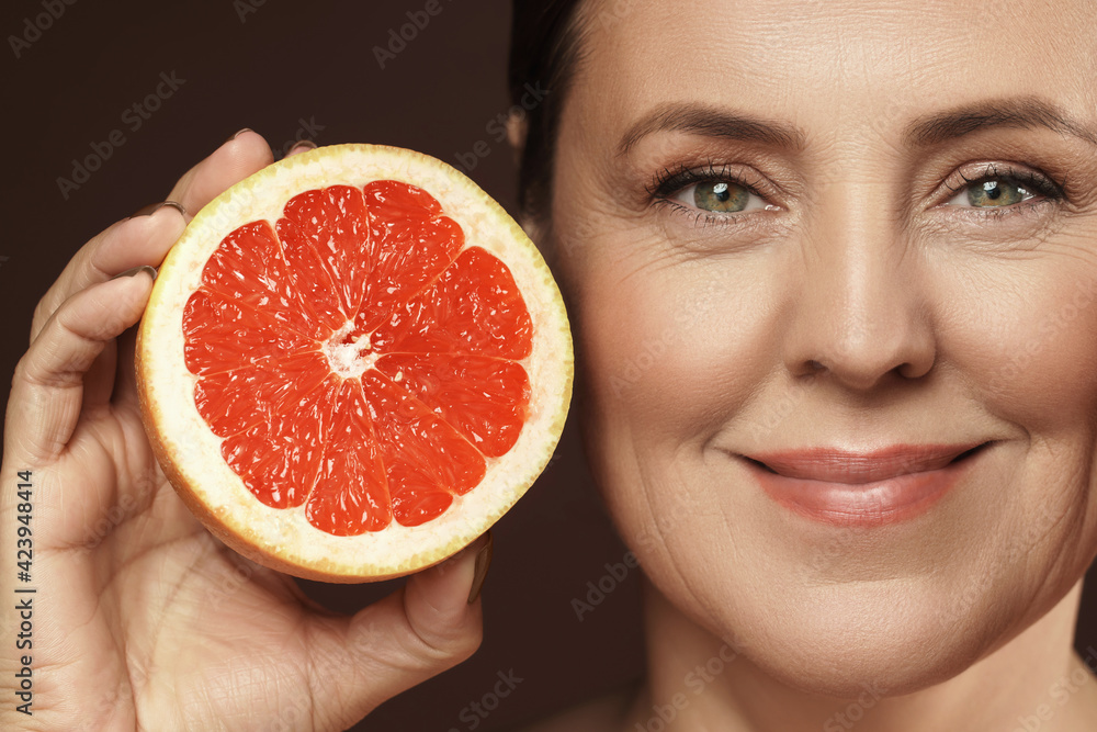 Foto de Beautiful and happy middle aged woman with a grapefruit in her ...