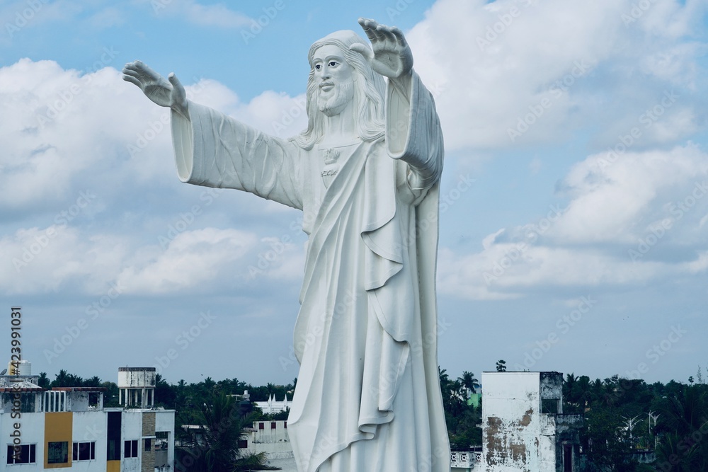 Jesus statue standing and blessing with both the hands against blue sky ...