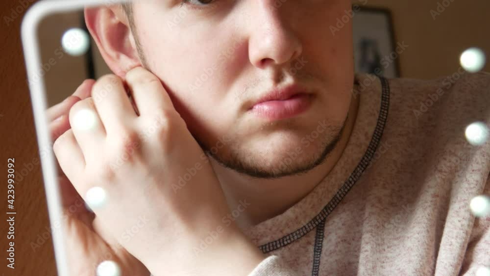 Vidéo Stock A young man inserts an earring into his ear while looking ...