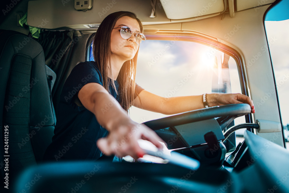 Portrait of beautiful young woman professional truck driver sitting and ...