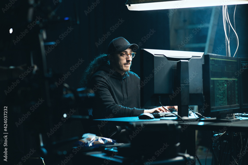 Concentrated and anxious Hacker wearing a sweatshirt and cap Breaking ...