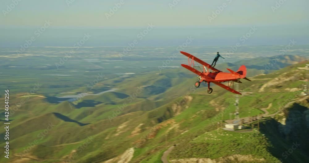 Stuntman stands atop vintage plane, aerial Stock Video | Adobe Stock