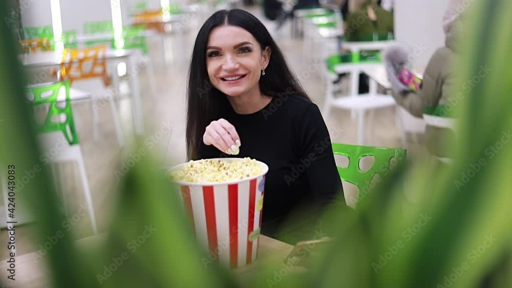 Young Girl is Sitting in the Cafe Before the Film She Eats Popcorn ...